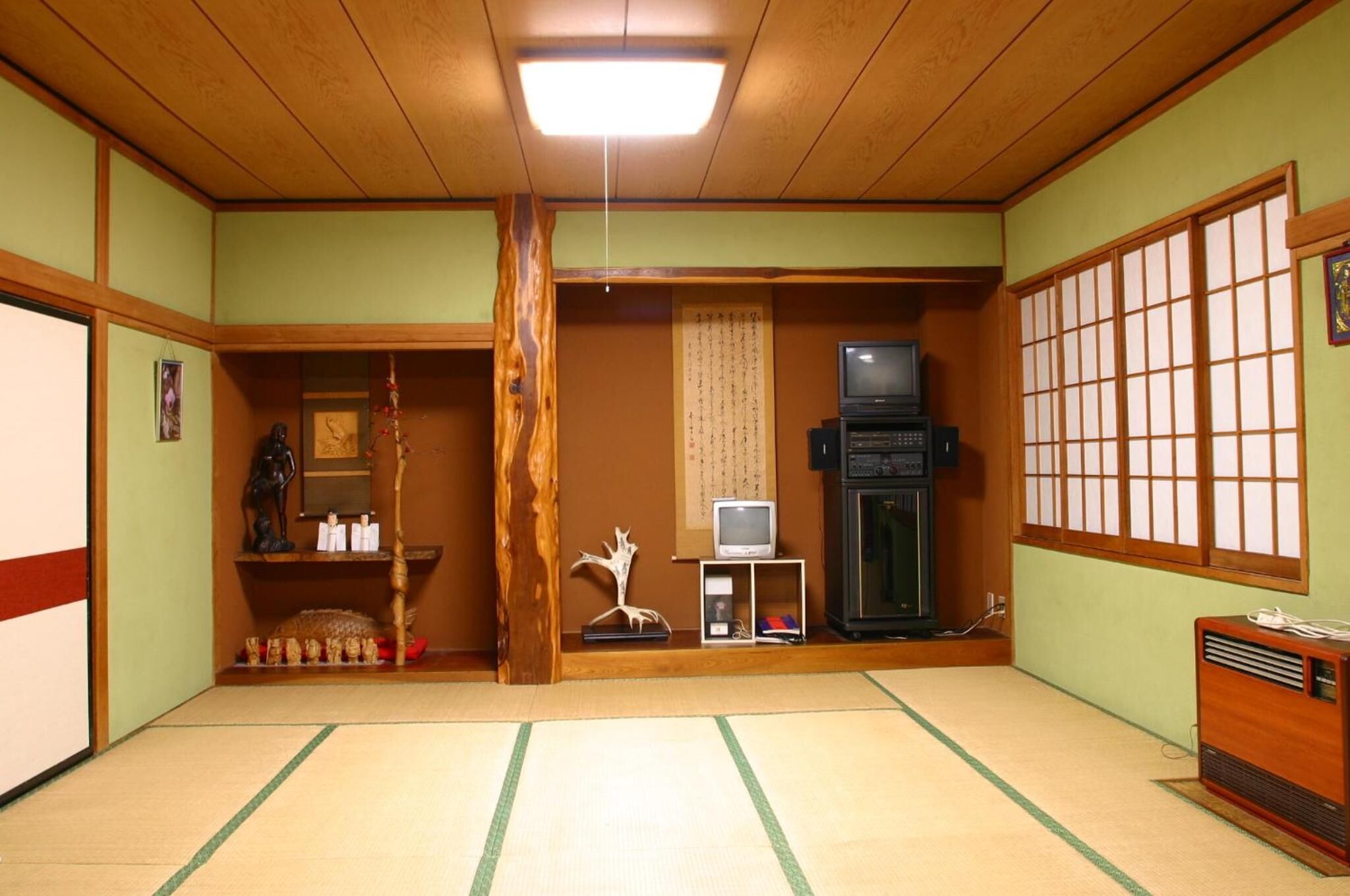Quarto japonês tradicional com tatames, televisão, aquecedor e um painel shoji.