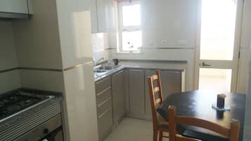 Apartamento, 3 quartos | Cozinha privada | Geladeira, micro-ondas, fogão, cooktop