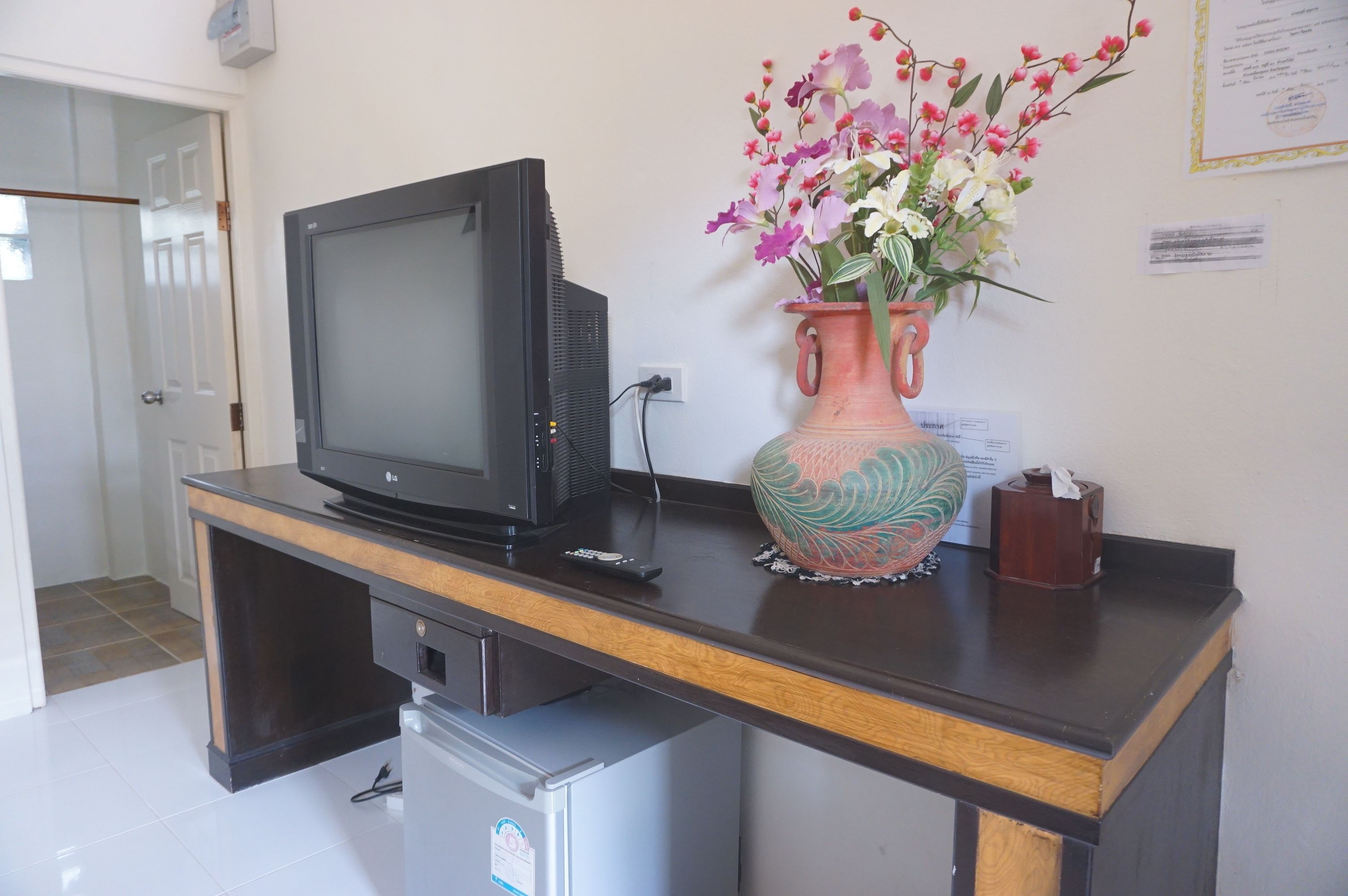 Uma televisão sobre uma mesa de madeira com um vaso de flores.