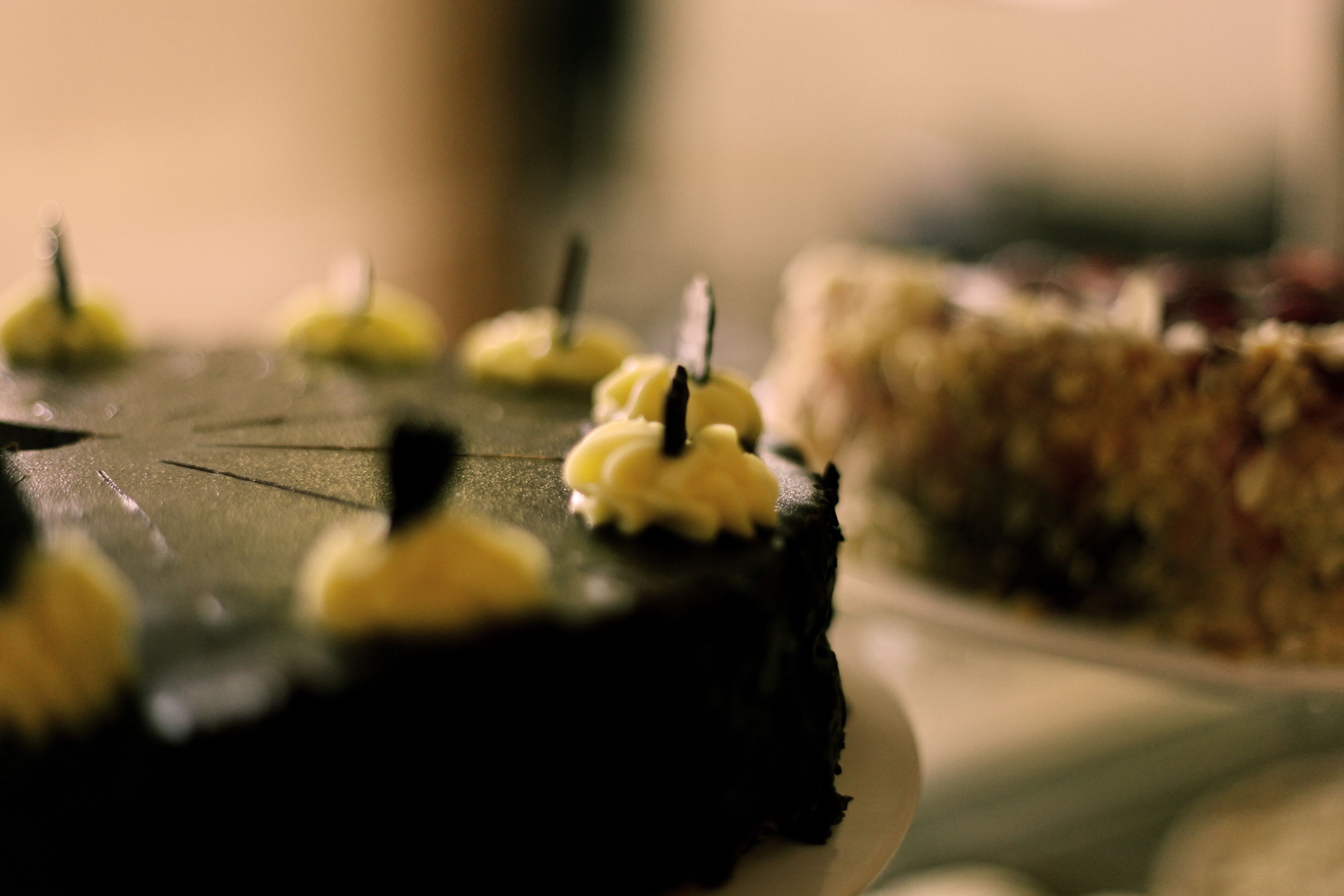 Um close-up de um bolo de chocolate com cobertura amarela e velas.