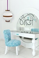 Quarto moderno com toucador branco, cadeira estampada e decoração de parede original.