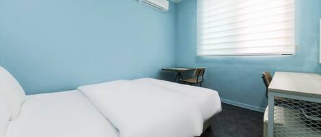 Um quarto com uma cama de solteiro, uma escrivaninha e uma cadeira.