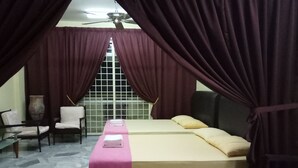 Quarto com duas camas, uma cadeira, uma mesa e uma janela com cortinas.