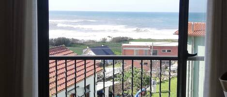Uma varanda com vista para o mar e uma área residencial.