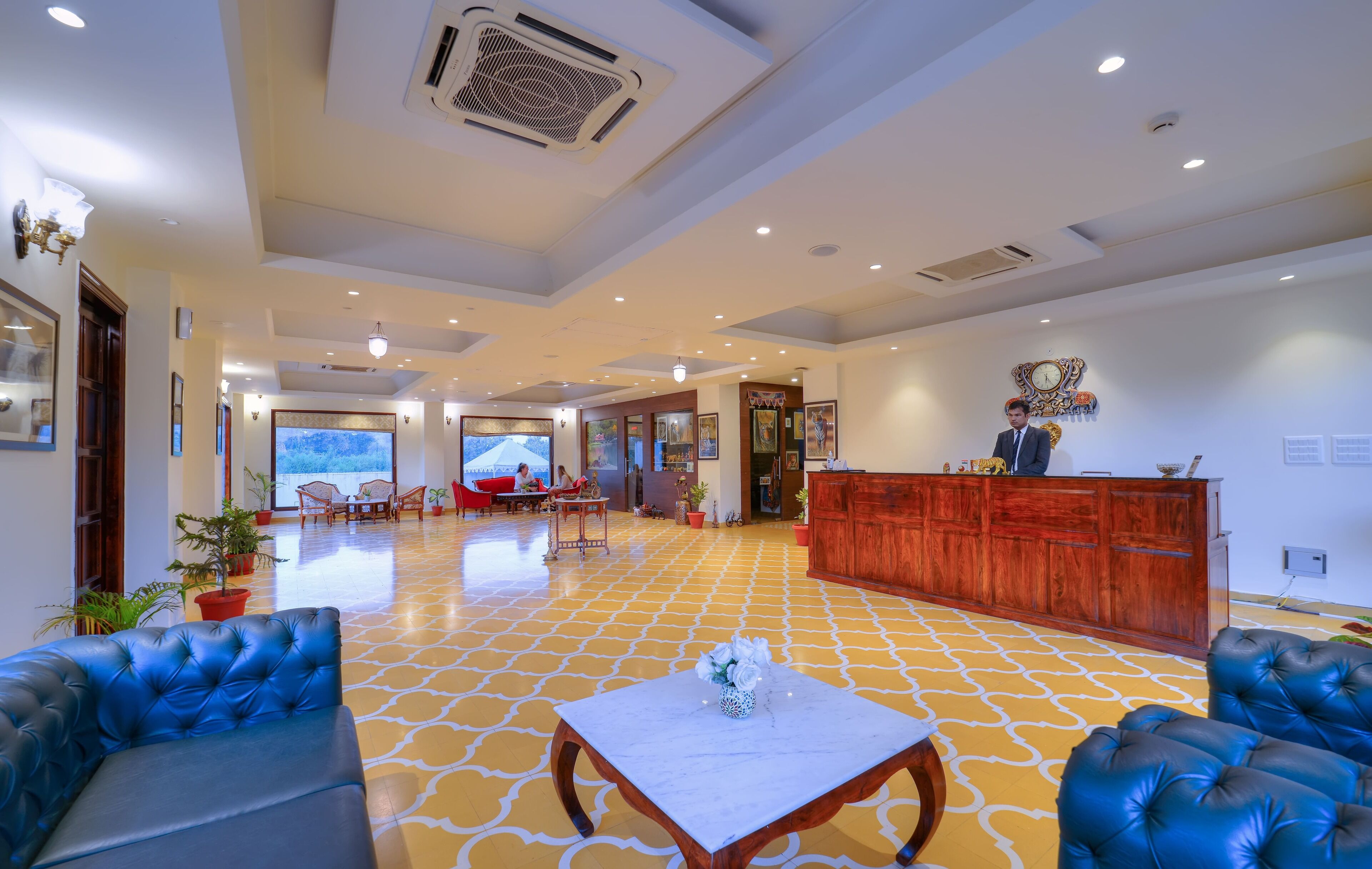 Um saguão de hotel com balcão de recepção, área de estar e obras de arte nas paredes.