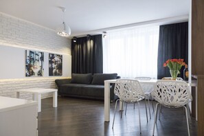 Uma sala de estar moderna com um sofá branco, uma mesa de jantar com cadeiras e obras de arte na parede.
