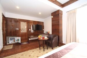 Quarto de hotel com uma cama, uma mesa pequena com itens de café da manhã, uma televisão na parede e painéis de madeira.