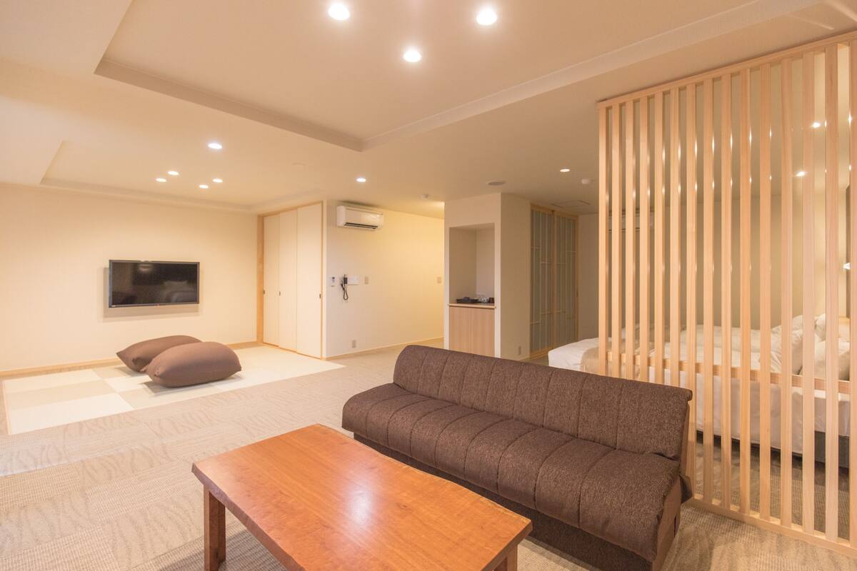 Uma sala de estar moderna com um sofá, uma mesa de madeira e uma TV fixada na parede.