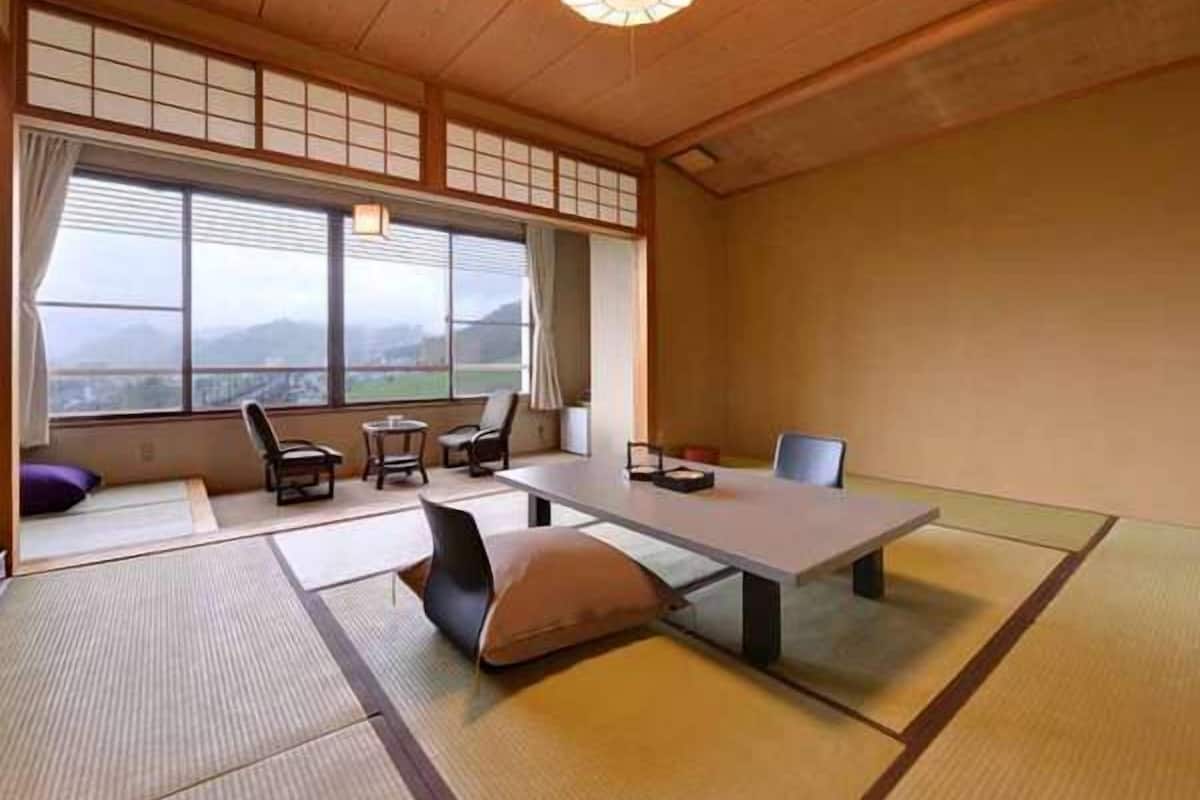 Um quarto japonês tradicional com piso de tatame, uma mesa baixa e cadeiras.