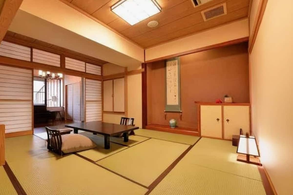 Um quarto japonês tradicional com tatames, uma mesa baixa e portas deslizantes.