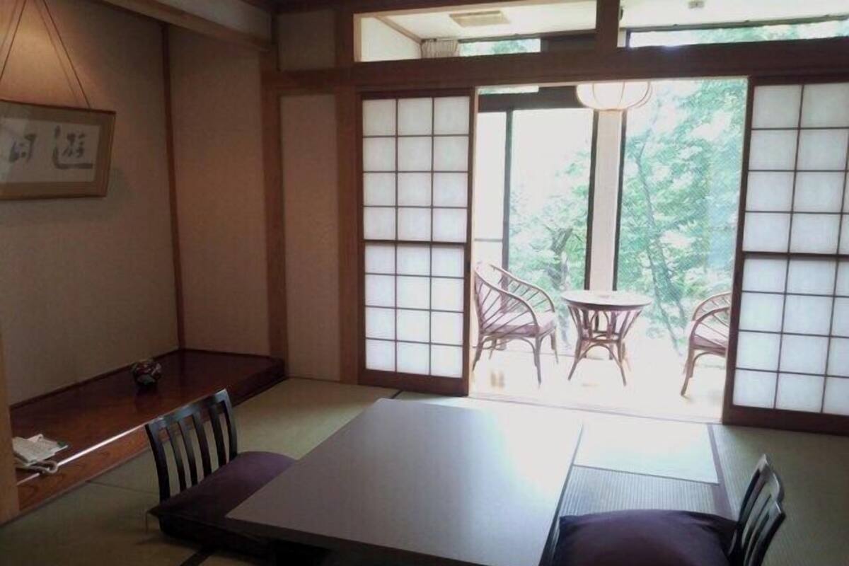Um quarto japonês tradicional com tatames, uma mesa baixa e portas deslizantes shoji.