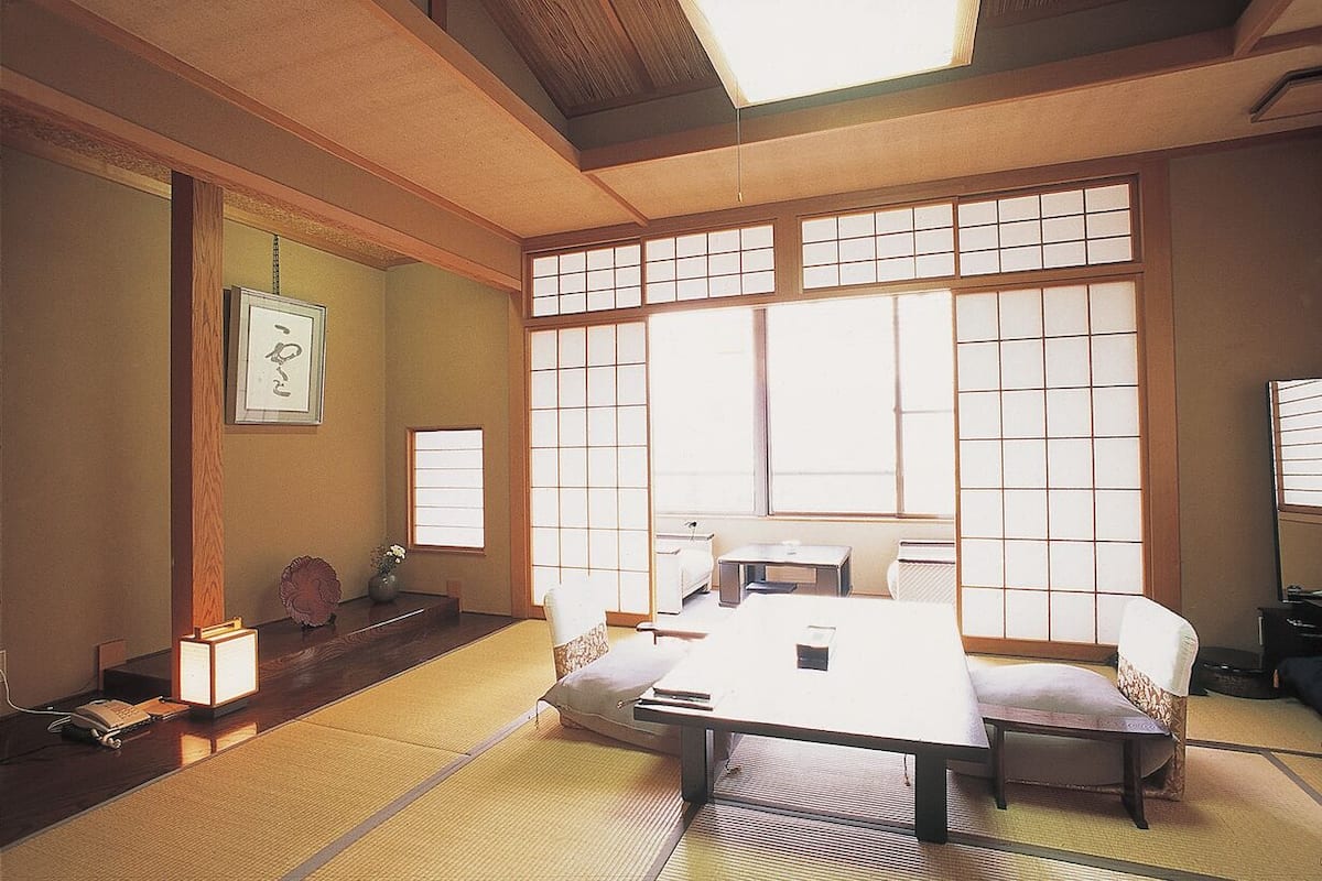 Um quarto japonês tradicional com tatames, uma mesa baixa, almofadas e portas deslizantes shoji.