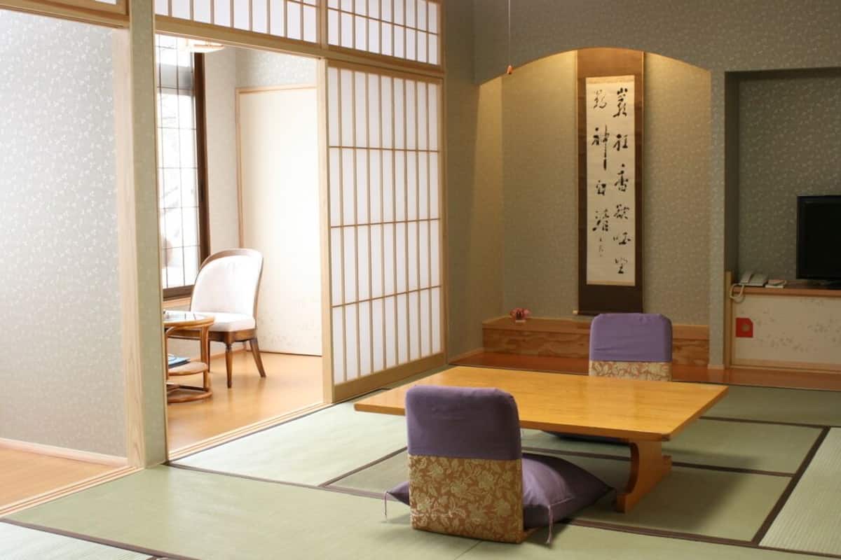 Um quarto japonês tradicional com tatame, uma mesa baixa e duas cadeiras com almofadas.