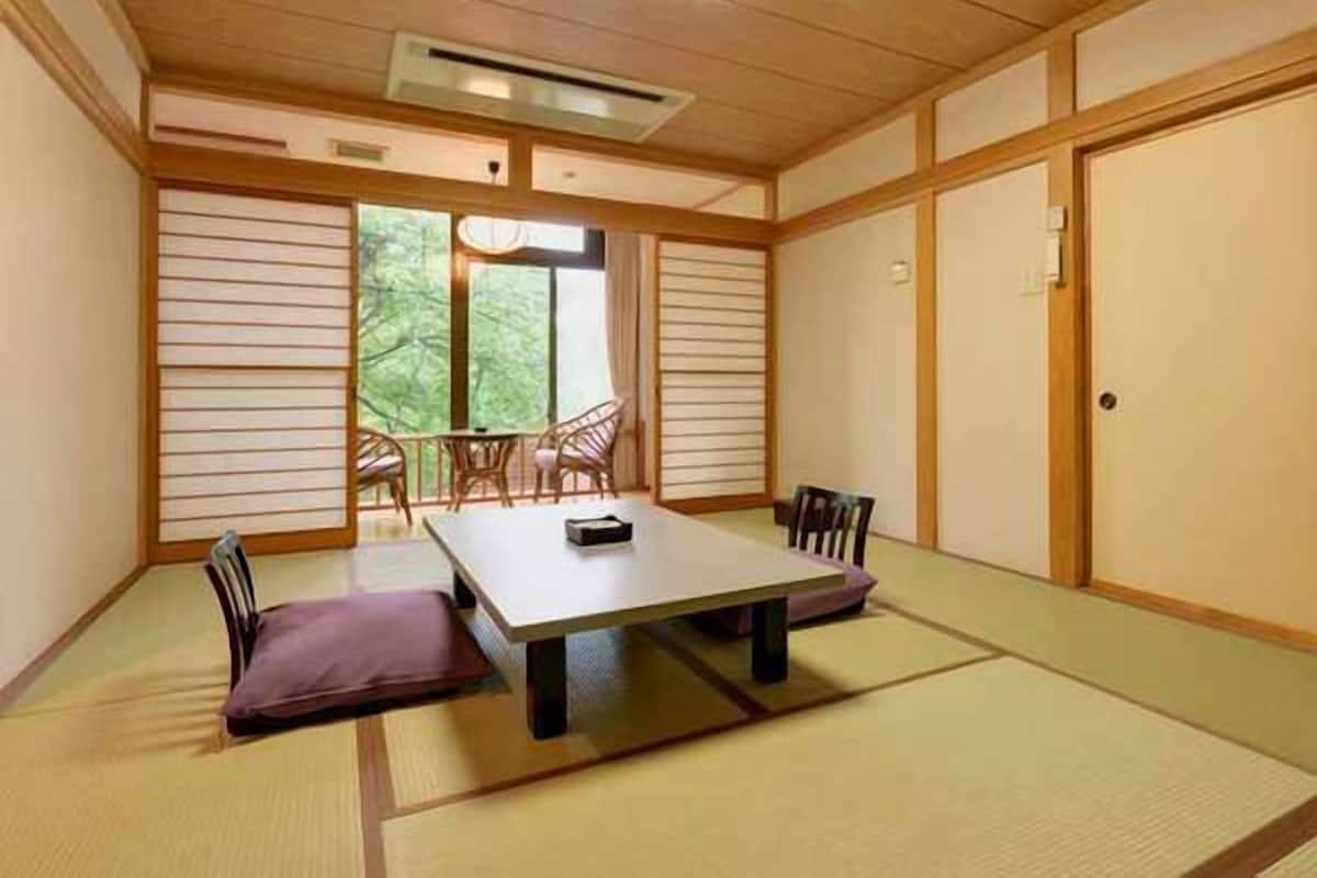 Um quarto japonês tradicional com tatames, uma mesa baixa e portas deslizantes.