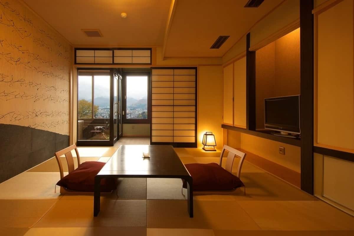 Quarto tradicional em estilo japonês, com tatames, uma mesa baixa e uma televisão sobre suporte.