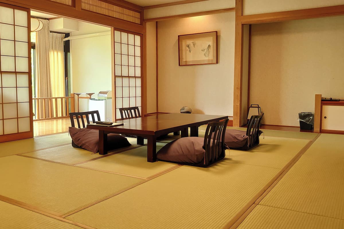 Um quarto japonês tradicional com tatames, uma mesa baixa e cadeiras de madeira.