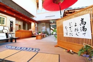 Interior japonês tradicional com esteiras de tatame, um balcão de recepção e um guarda-chuva vermelho.