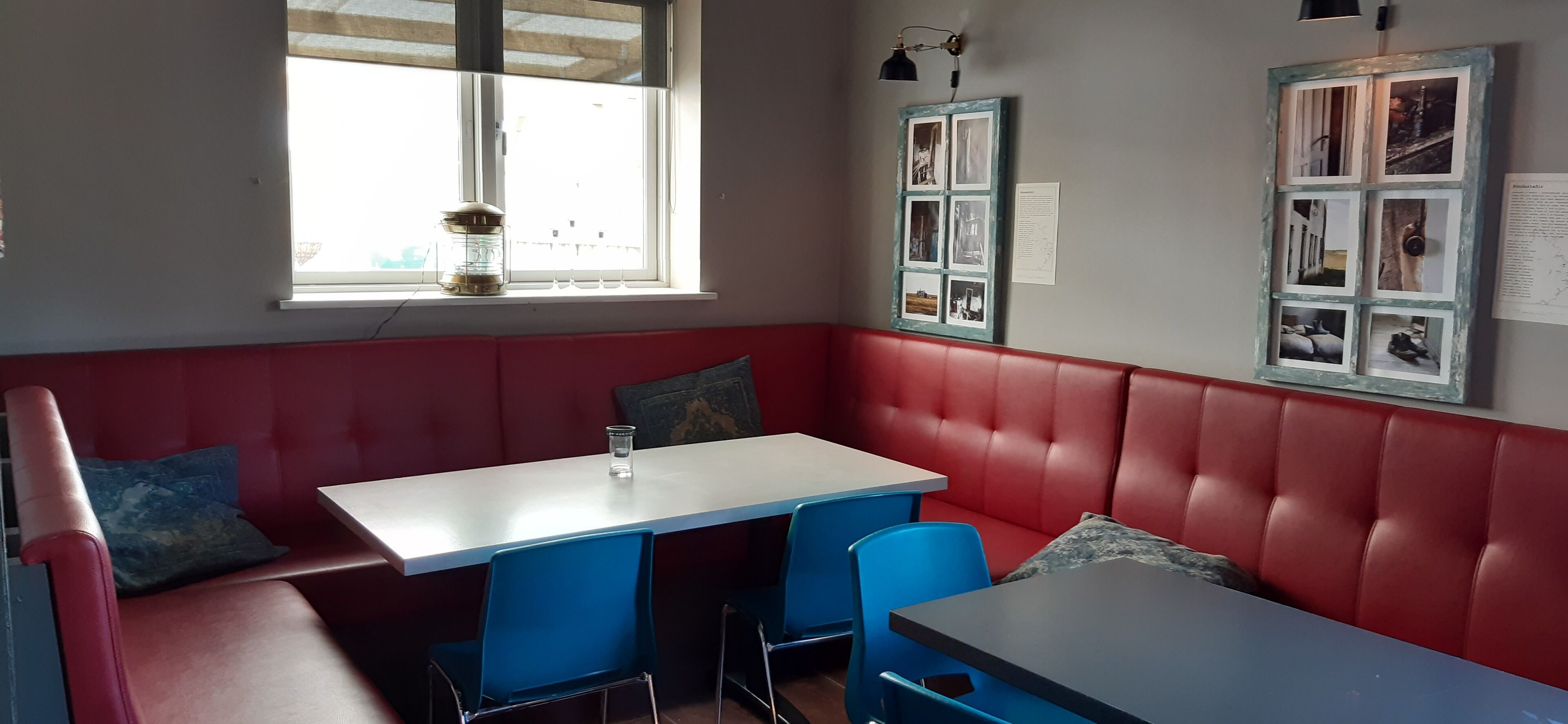 Uma área de estar com um banco acolchoado vermelho, uma mesa branca e cadeiras azuis.