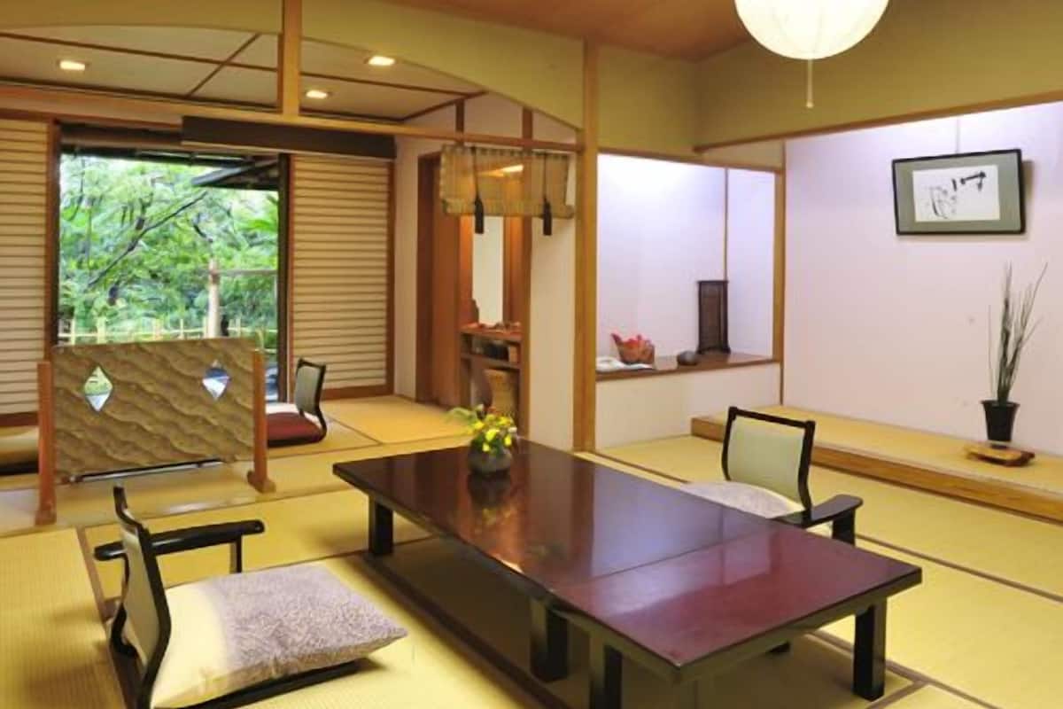 Um quarto japonês tradicional com tatames, uma mesa baixa e portas deslizantes.