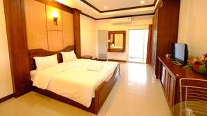 Quarto de hotel com uma cama grande, televisão, espelho e escrivaninha com cadeira.