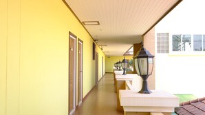 Um corredor com paredes amarelas, portas de madeira e piso de azulejos.