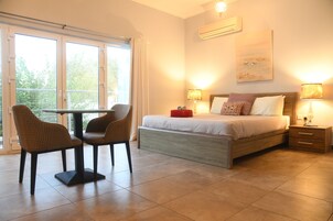 Quarto com cama, mesas de cabeceira, uma mesa e cadeiras.