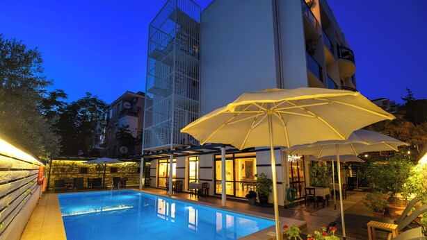 Piscina com deck de madeira, área de estar ao ar livre e guarda-sóis.