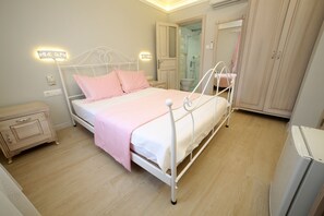 Um quarto com cama, mesa de cabeceira, guarda-roupa e espelho.