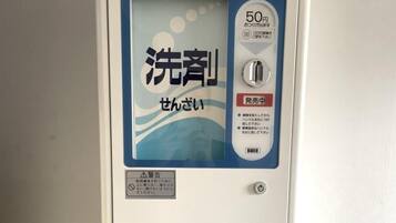 Máquina de vendas automática com texto em japonês, entrada para moeda de 50 ienes e um botão com a inscrição '発売中' (em estoque).