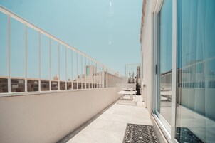 Varanda com guarda-corrimão branco, um banco e uma porta para um edifício.
