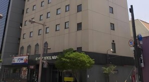 Um hotel de vários andares com fachada moderna, entrada visível e placa indicando proibido estacionar.