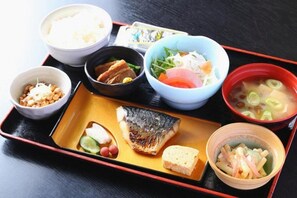 Bandeja com diversos pratos japoneses, incluindo arroz, peixe e sopa.