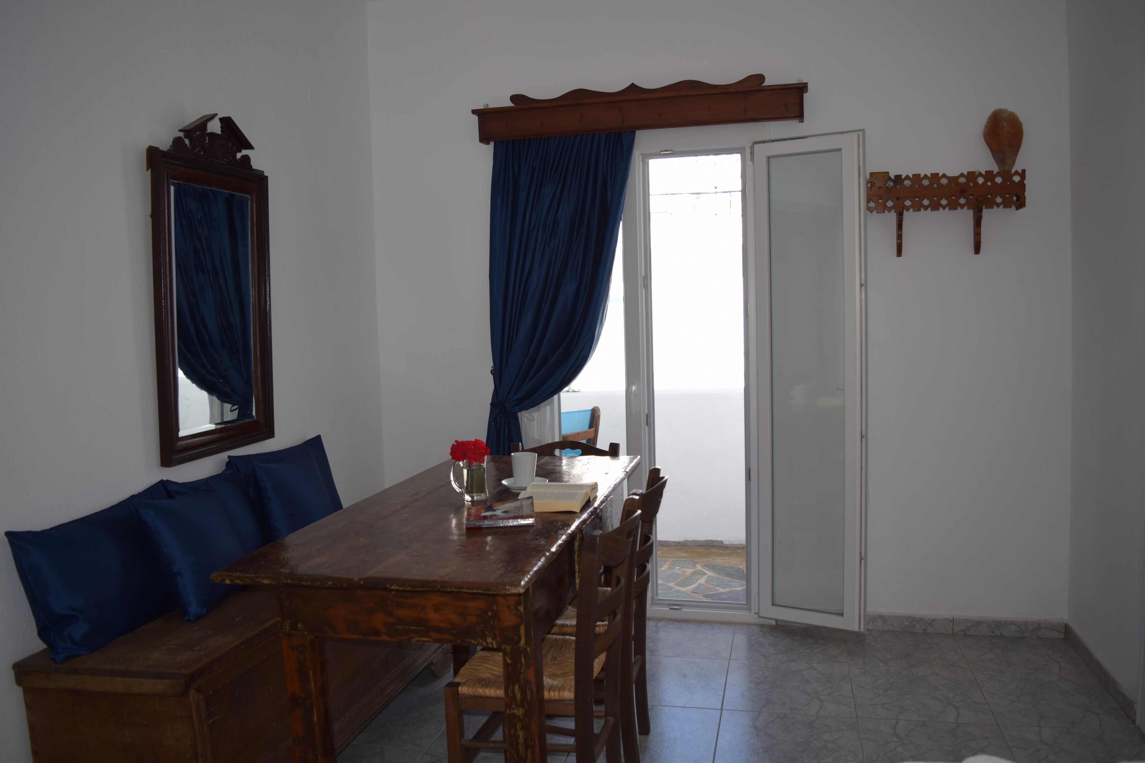 Uma sala de jantar com mesa de madeira, cortinas azuis e um banco.