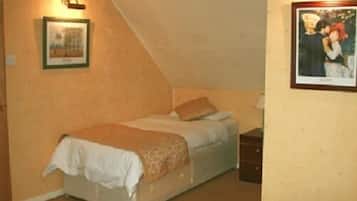 Quarto com cama, mesa de cabeceira, quadro pendurado na parede e luminária suspensa.