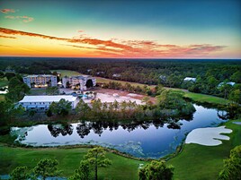 Um hotel grande com vários edifícios, campo de golfe e um lago.