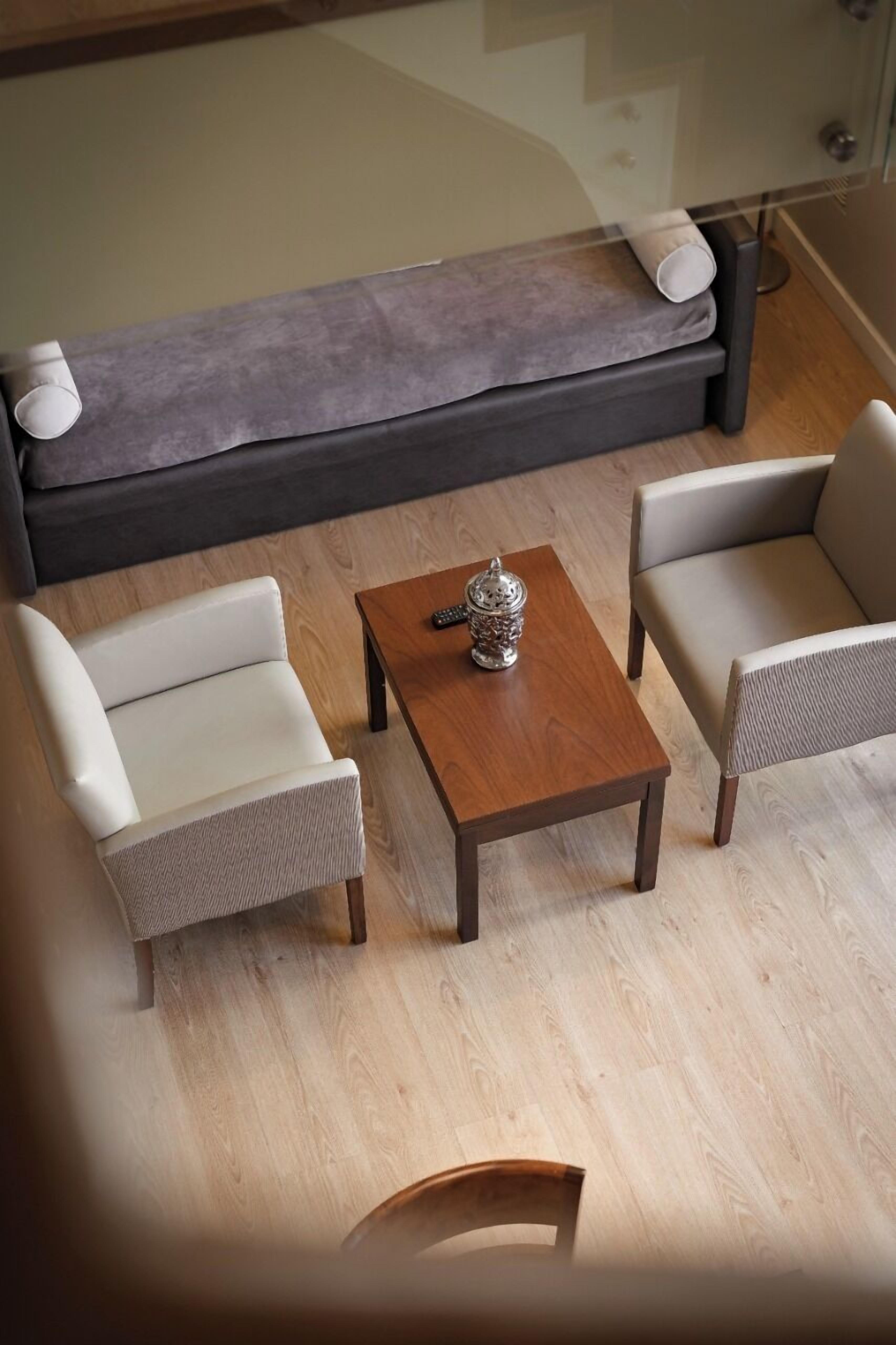 Uma sala de estar moderna com sofá, duas poltronas, uma mesa de centro e uma porta de vidro que dá para um banheiro.