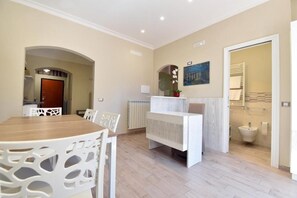 Decoração moderna com área de refeições, uma recepção em branco e um banheiro visível por uma porta aberta.