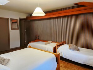 Quarto com duas camas de madeira, uma parede de ripas de madeira e um lustre.
