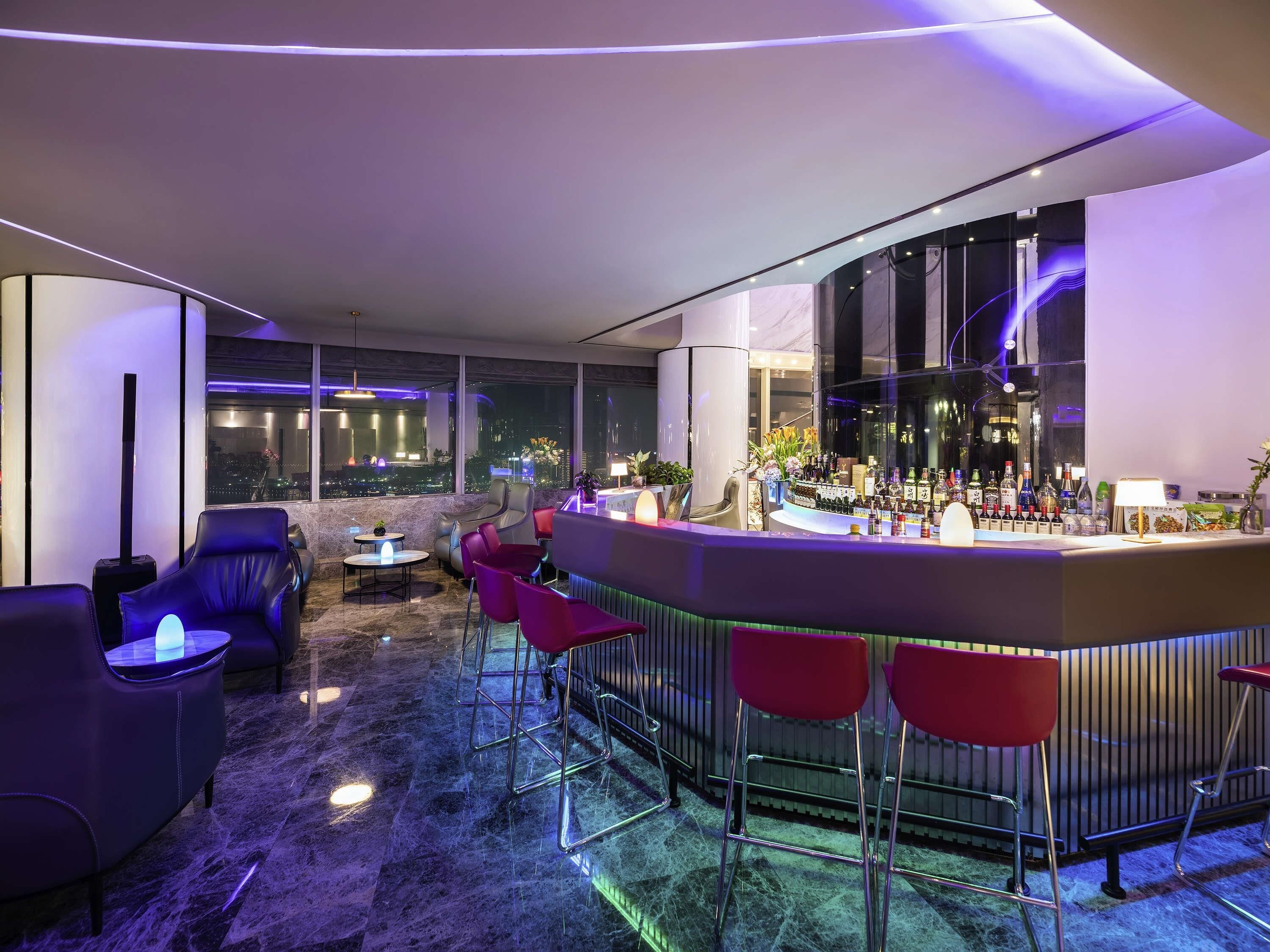 Uma área de bar moderna com assentos e vista para a cidade.