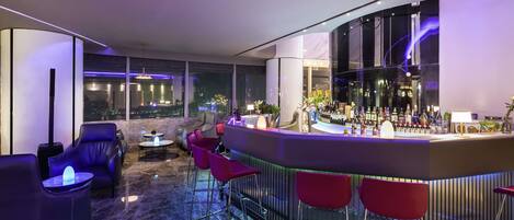 Uma área de bar moderna com assentos e vista para a cidade.