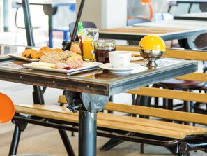 Uma mesa de café da manhã com diversos alimentos, uma xícara de café e um copo de suco.
