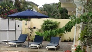 Uma piscina com espreguiçadeiras e um guarda-sol.