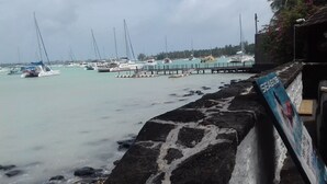 Uma marina com barcos atracados, um cais e um muro de pedra com uma placa.