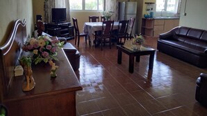Uma sala de estar com sofá, mesa de centro, televisão e um espaço de jantar com cadeiras e mesa.