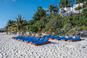 Na praia, praia de areia branca, espreguiçadeiras, guarda-sóis de praia