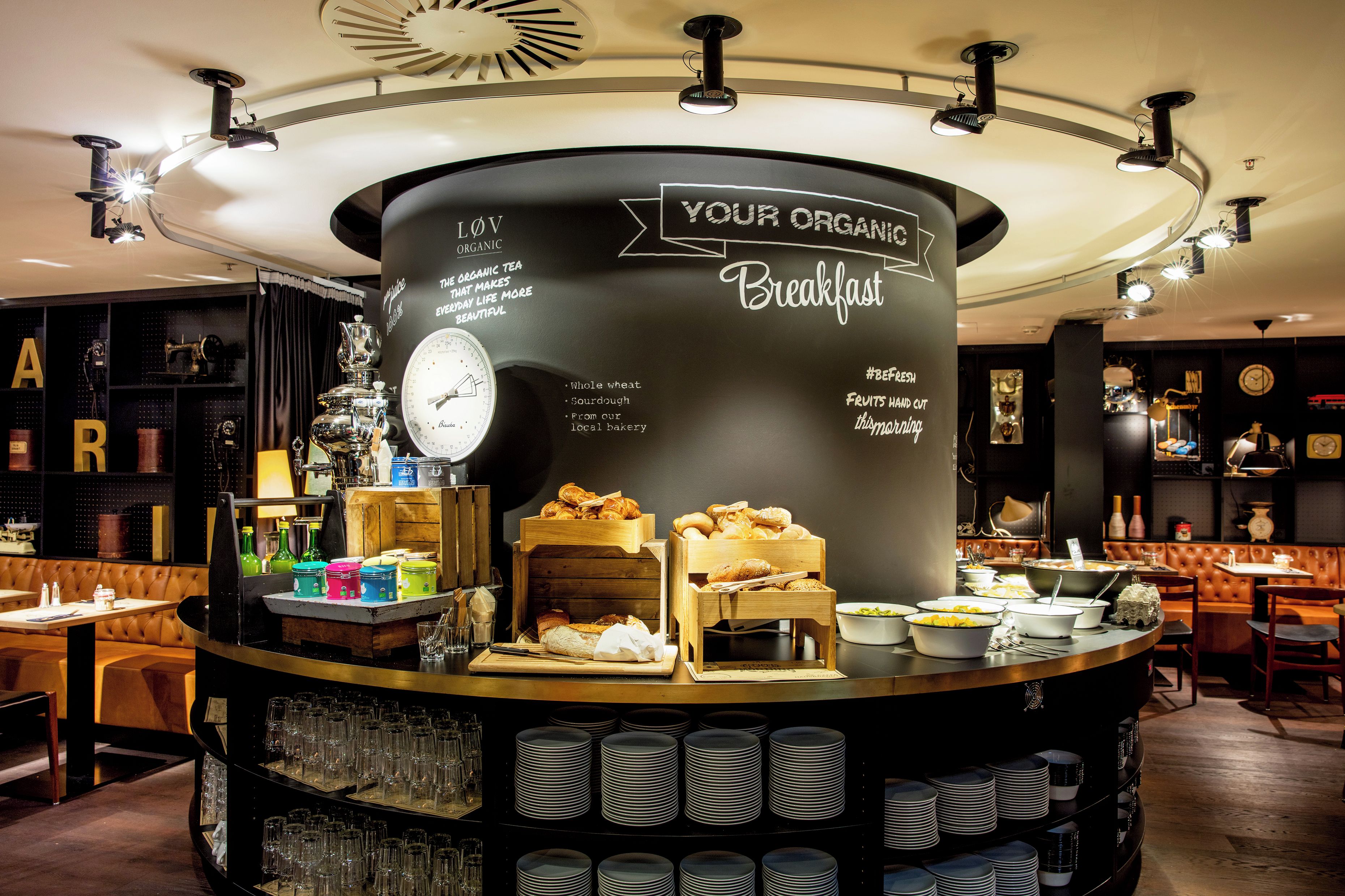 Balcão de café da manhã com relógio, pão integral, sourdough e produtos de padaria local.