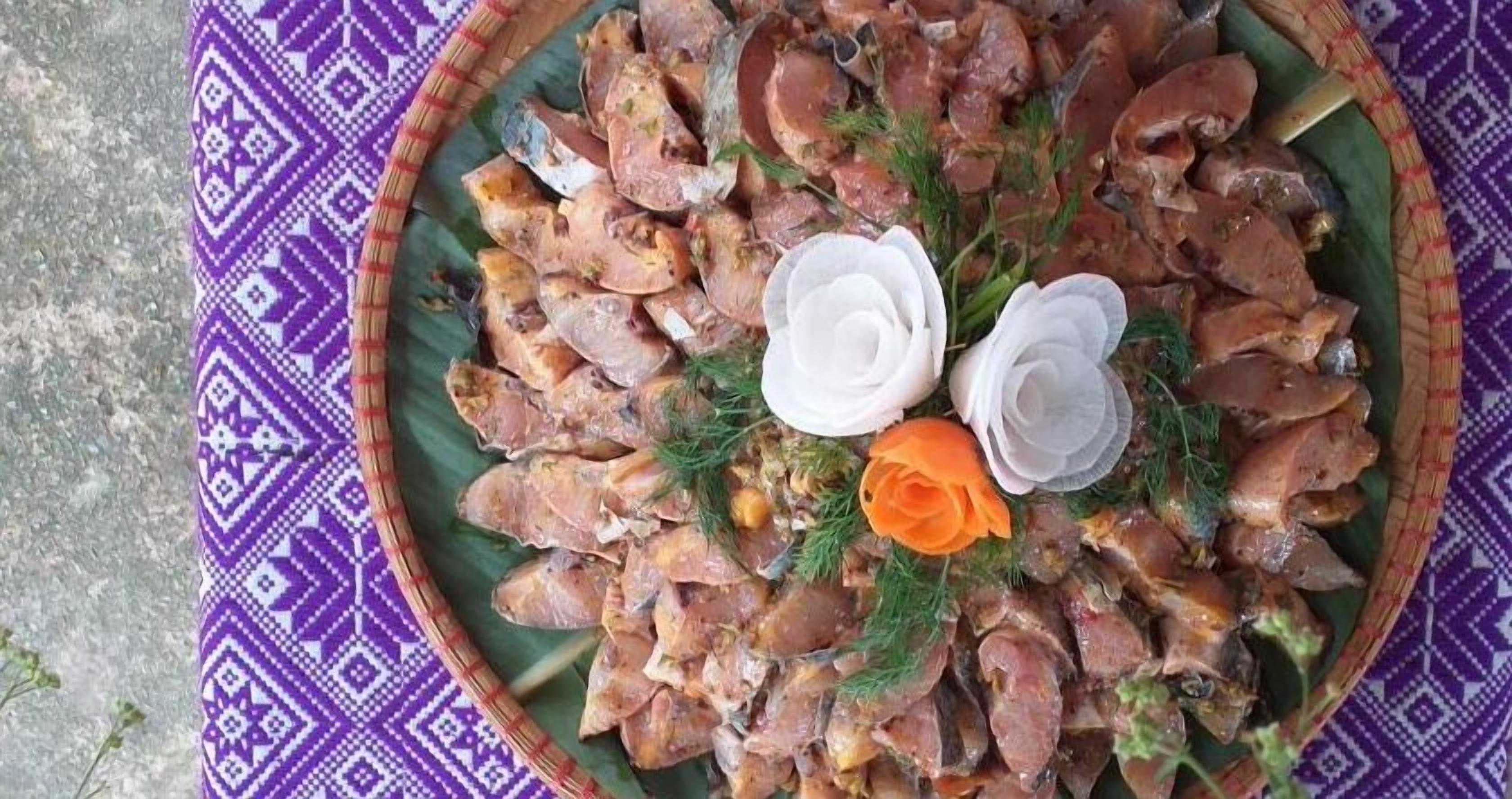 Prato tradicional com carne e flores sobre um prato trançado.