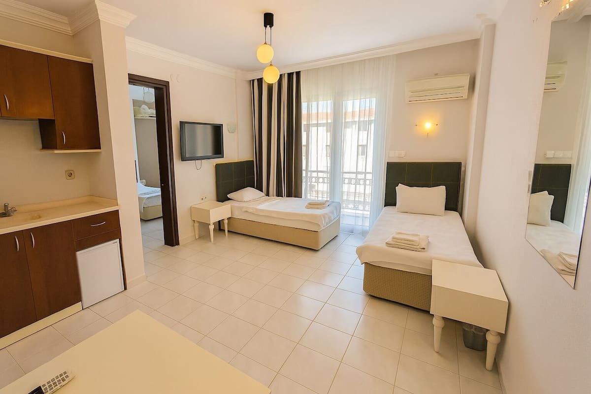 Quarto de hotel com duas camas, televisão, frigobar e banheiro.