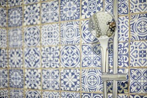 Chuveiro com um acessório de chuva fixado em parede com azulejos estampados em azul e branco.