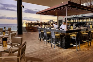 Área de bar com vista para o oceano, banquetas e placa indicando Daiquiri.